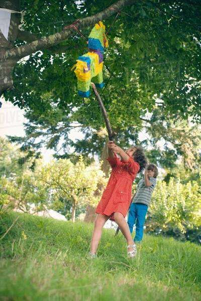 Girl swinging at pinata at party - Stock Photo - Dissolve