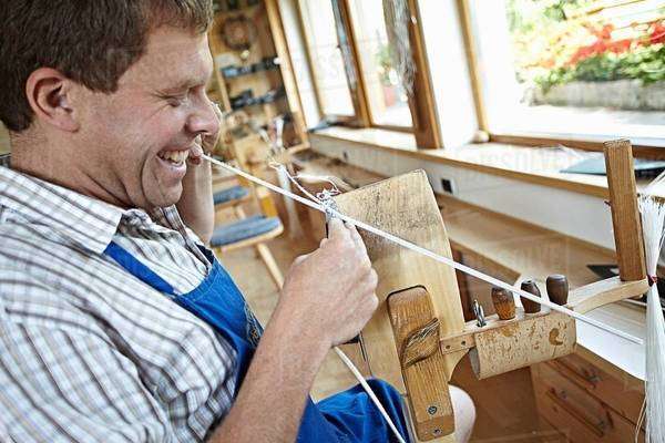 Worker laughing while weaving in shop - Stock Photo - Dissolve