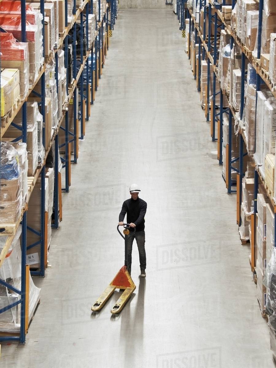 Worker operating dolly in warehouse - Stock Photo - Dissolve