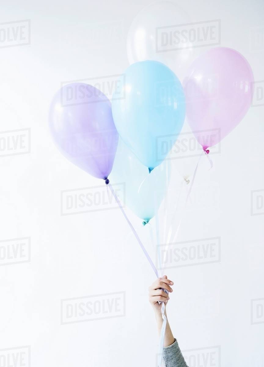 Hand holding bunch of balloons - Stock Photo - Dissolve