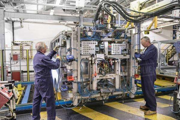 Car workers assembling vehicle in car plant - Stock Photo - Dissolve