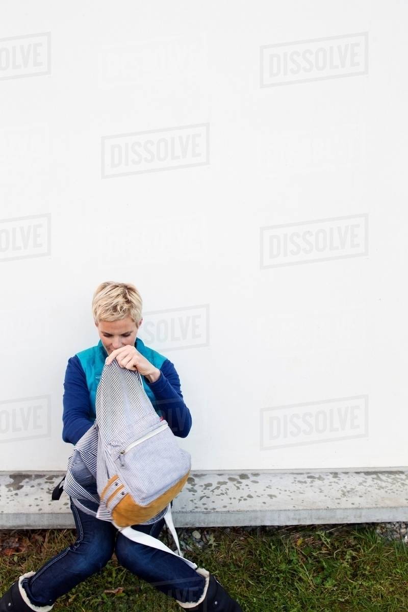Woman digging through backpack - Royalty-free Stock Photo | Dissolve