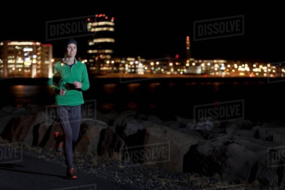 Woman running on waterfront at night - Stock Photo - Dissolve