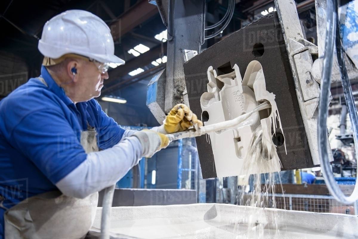 Worker coating sand mould in foundry - Stock Photo - Dissolve