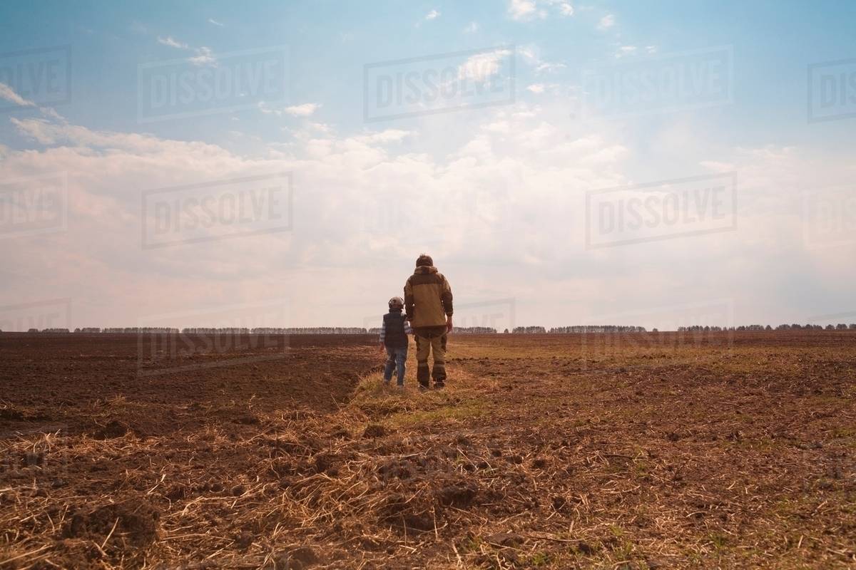 Father and son standing together in field, rear view - Stock Photo ...