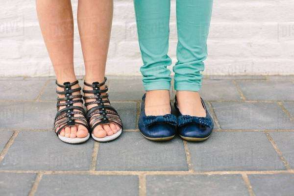 Close up of two sisters legs and footwear - Stock Photo - Dissolve