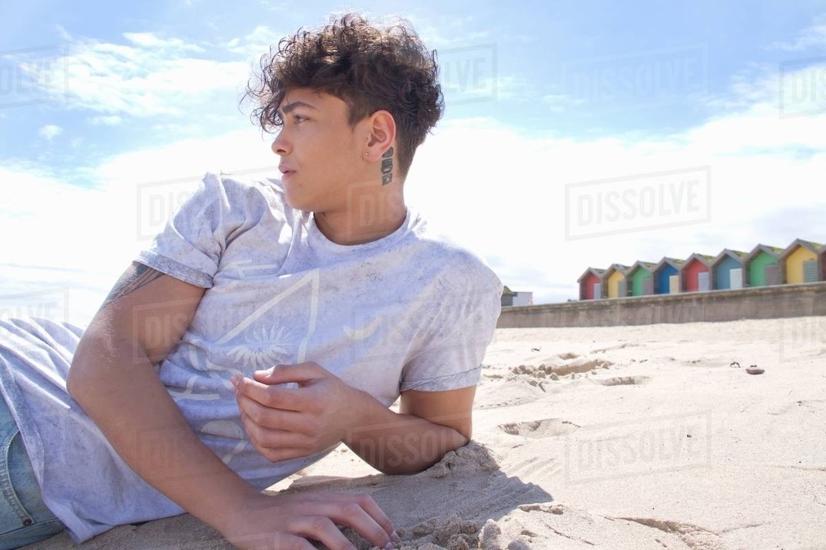 Portrait of young man lying on beach - Royalty-free Stock Photo | Dissolve