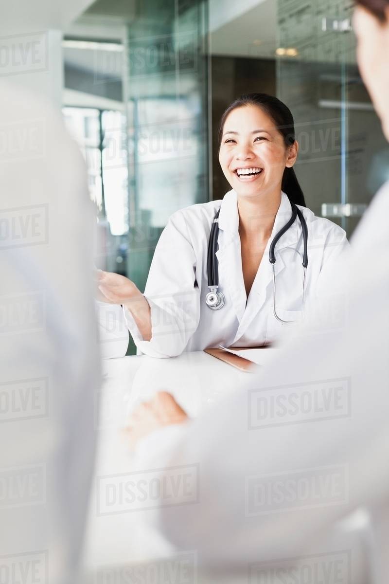 Doctor talking to colleagues in meeting - Stock Photo - Dissolve