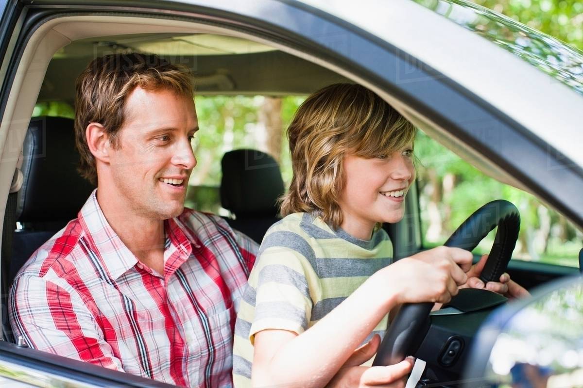 Boy driving car on fathers lap - Stock Photo - Dissolve