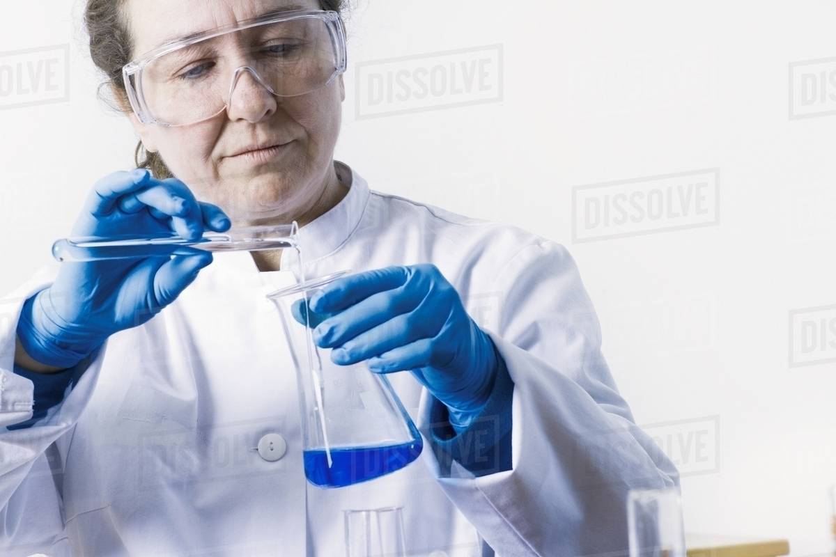 Scientist pouring liquid into beaker - Royalty-free Stock Photo | Dissolve