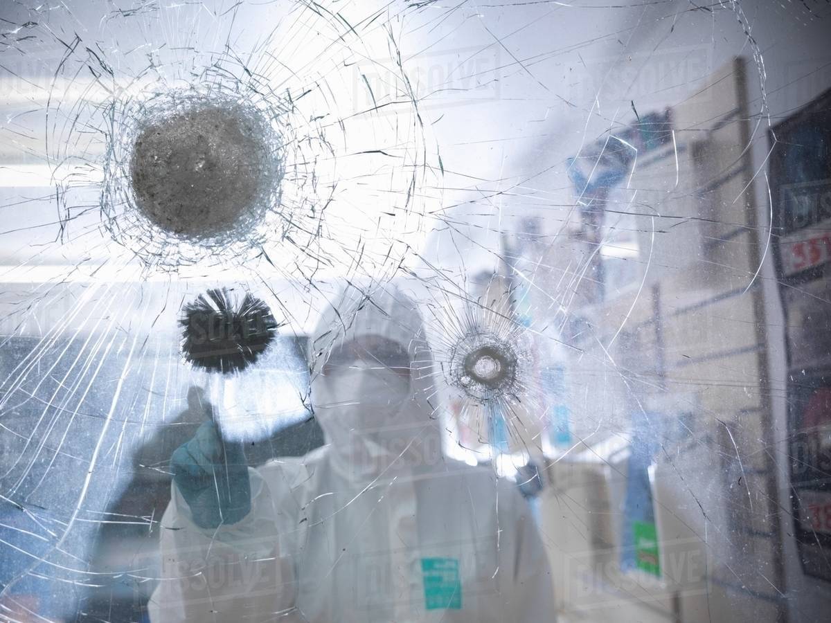 Forensic scientist dusting for fingerprints in broken glass at crime ...