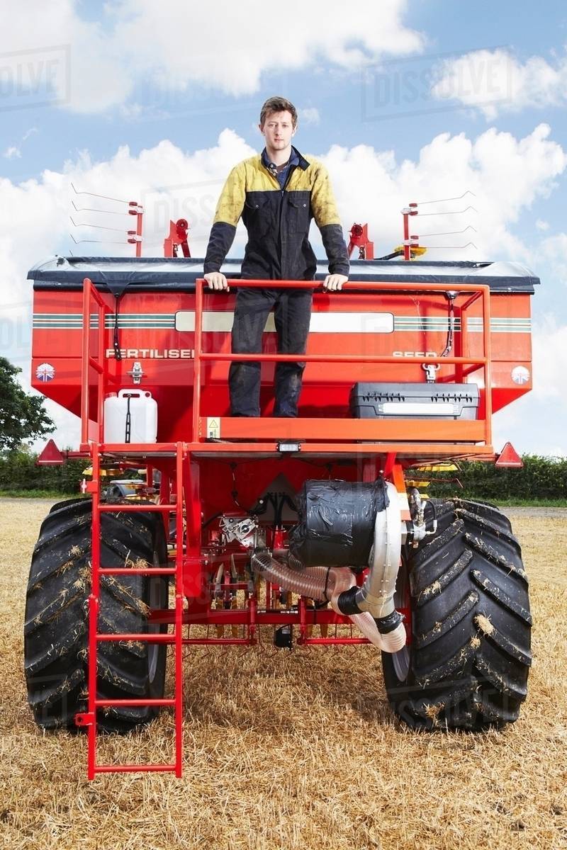Farmer standing on tractor in field - Royalty-free Stock Photo | Dissolve