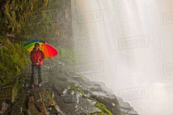 Woman standing under waterfall in forest - Stock Photo - Dissolve