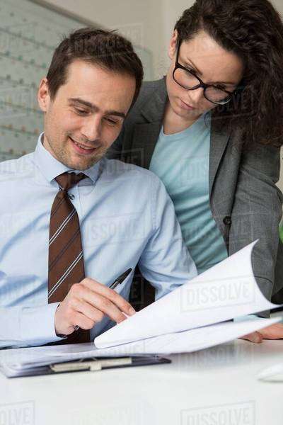 Businesspeople smiling looking at paperwork - Stock Photo - Dissolve