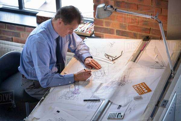 Architect drawing plans at drawing board - Stock Photo - Dissolve