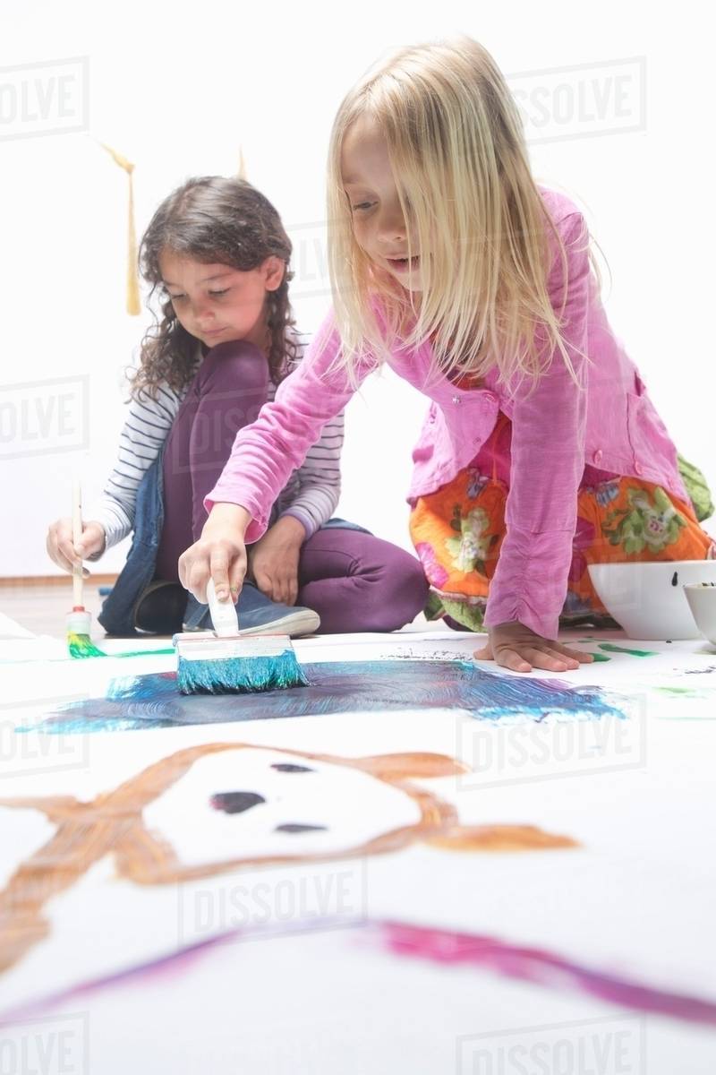 Two girls painting on floor - Royalty-free Stock Photo | Dissolve