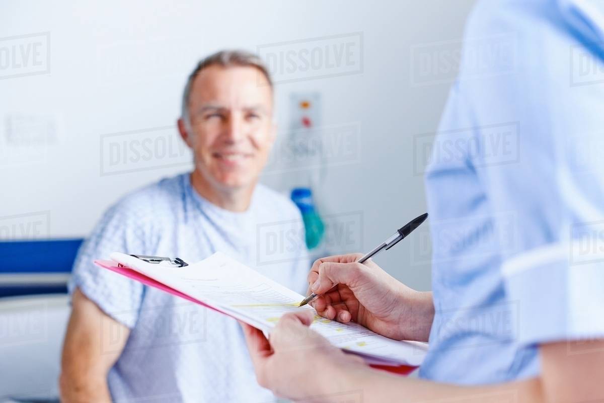 Nurse completing paperwork, patient in background - Royalty-free Stock ...