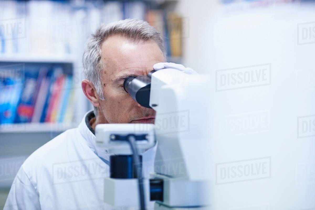 Man looking through microscope - Royalty-free Stock Photo | Dissolve