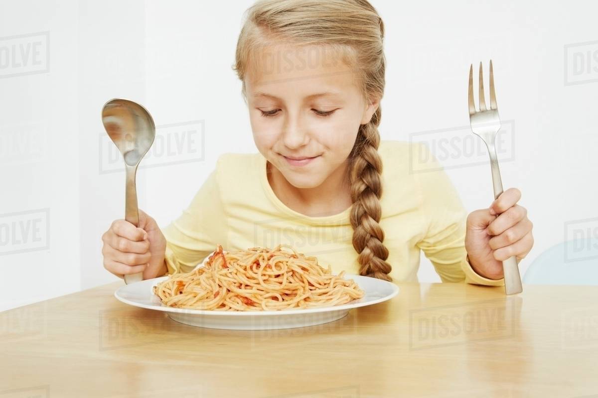 Girl with plate of spaghetti and oversized cutlery - Stock Photo - Dissolve
