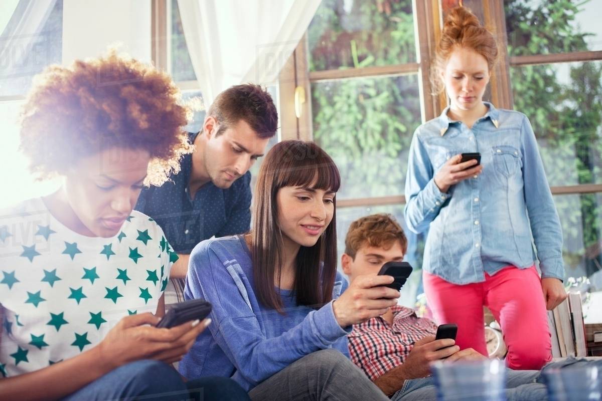 Group of friends using smartphones - Royalty-free Stock Photo | Dissolve