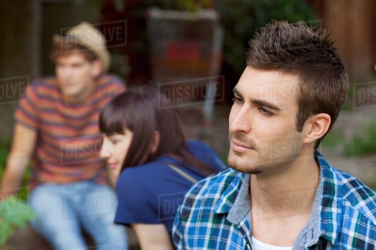 Portrait of young man with friends in background - Stock Photo - Dissolve