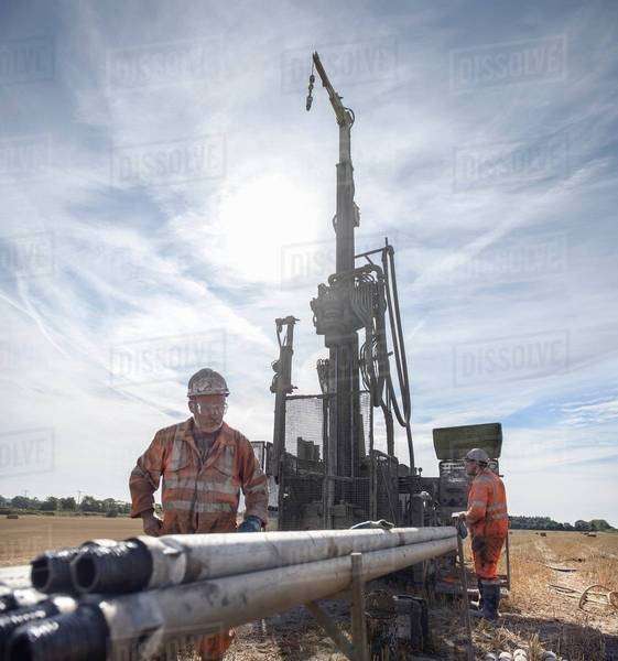 Workers operating drilling rig in field - Stock Photo - Dissolve