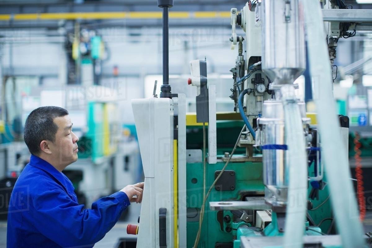 Worker at small parts manufacturing factory in China, pressing button ...