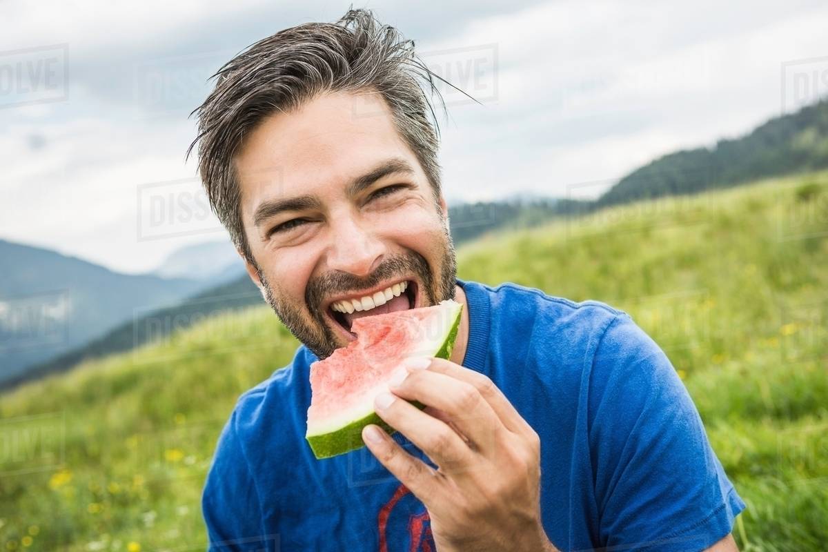 Man biting into watermelon - Stock Photo - Dissolve