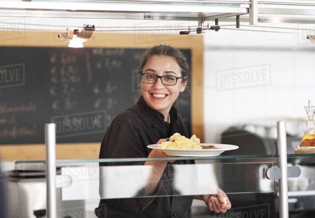 Woman working in restaurant kitchen, serving meal - Royalty-free Stock ...