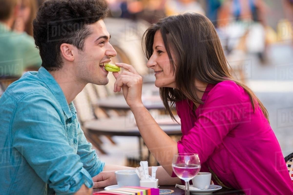 Young couple eating macaron at pavement cafe, Paris, France - Royalty ...
