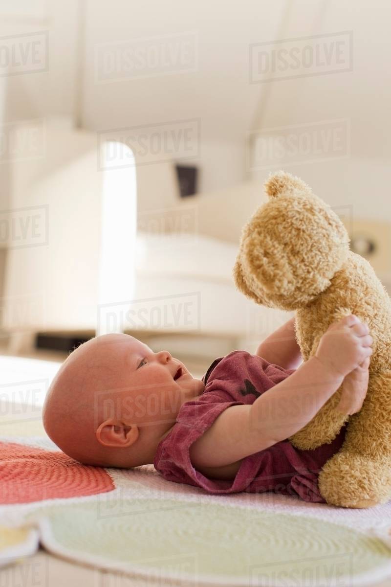 Baby girl playing with teddy bear - Royalty-free Stock Photo | Dissolve