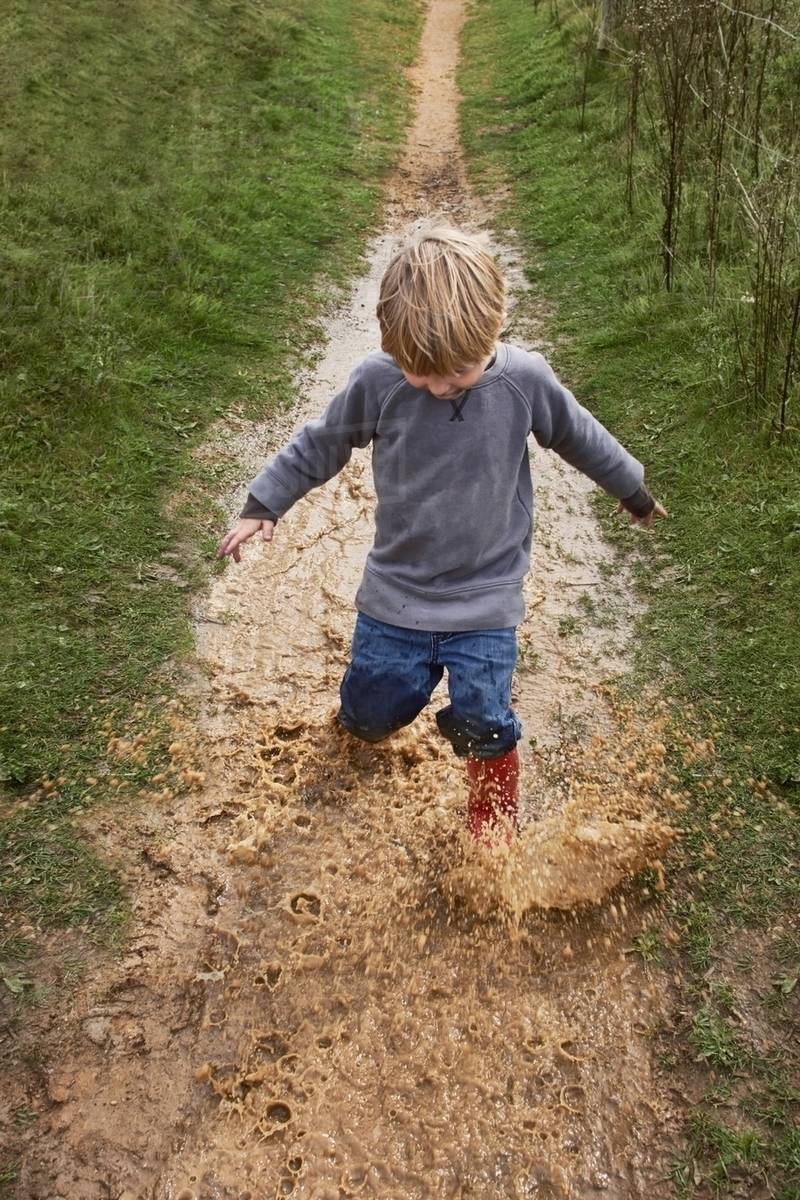 Boy splashing through muddy puddle - Royalty-free Stock Photo | Dissolve