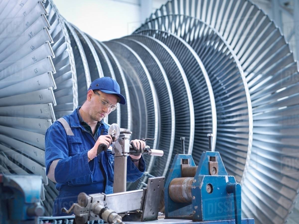 Engineer at workstation in front of steam turbine - Stock Photo - Dissolve