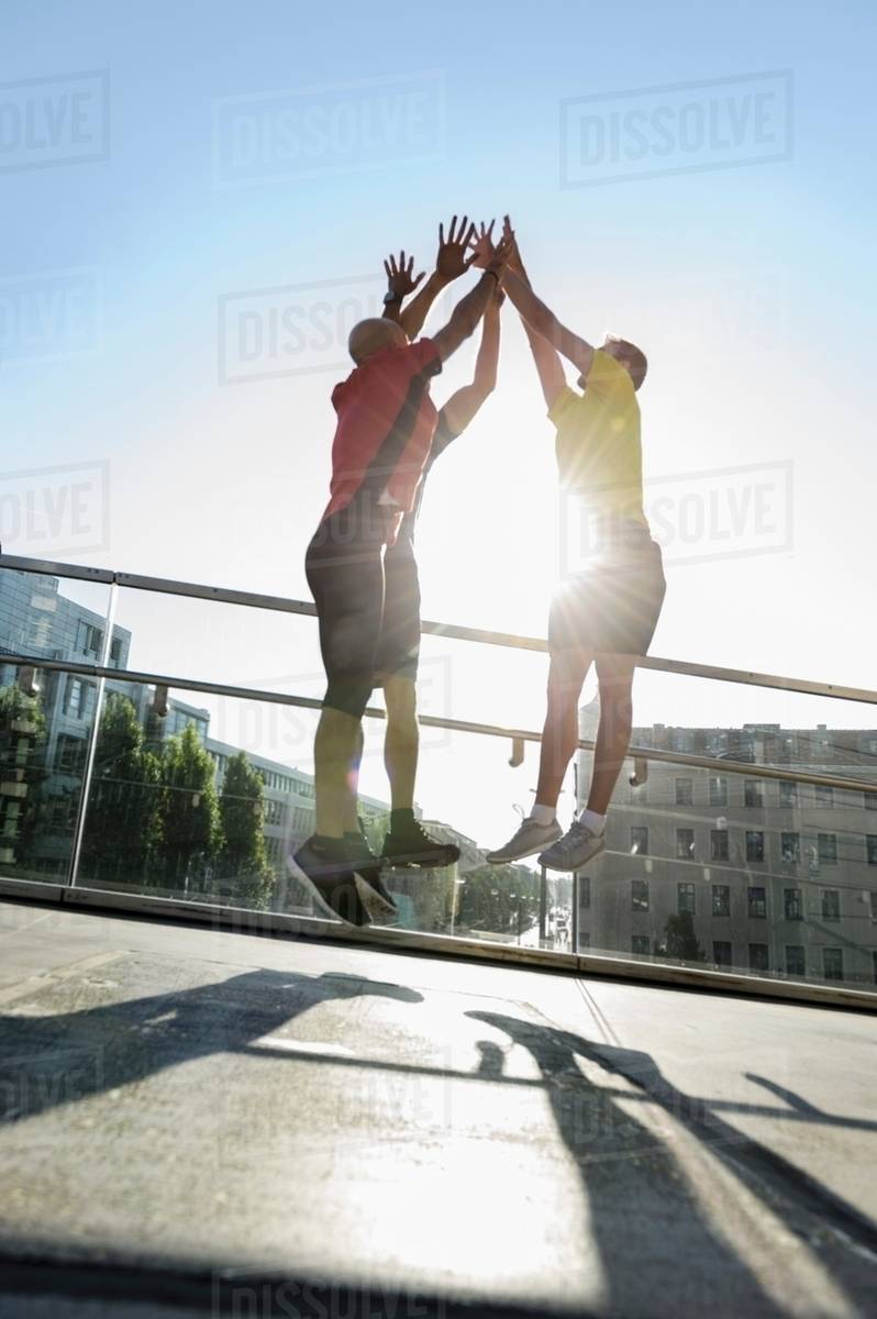 Runners jumping doing hi-five, Munich, Germany - Stock Photo - Dissolve