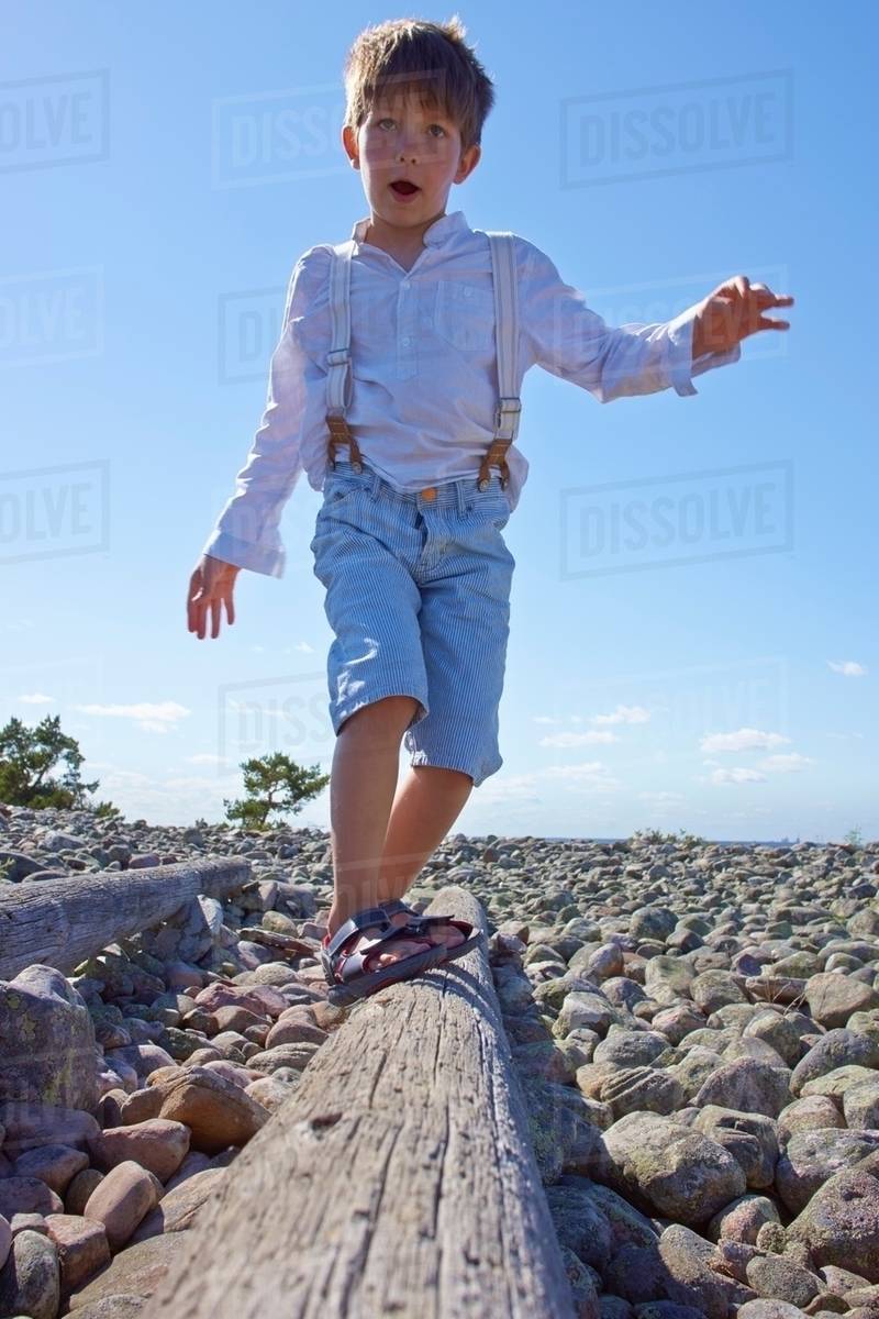 Boy balancing on log on beach - Royalty-free Stock Photo | Dissolve