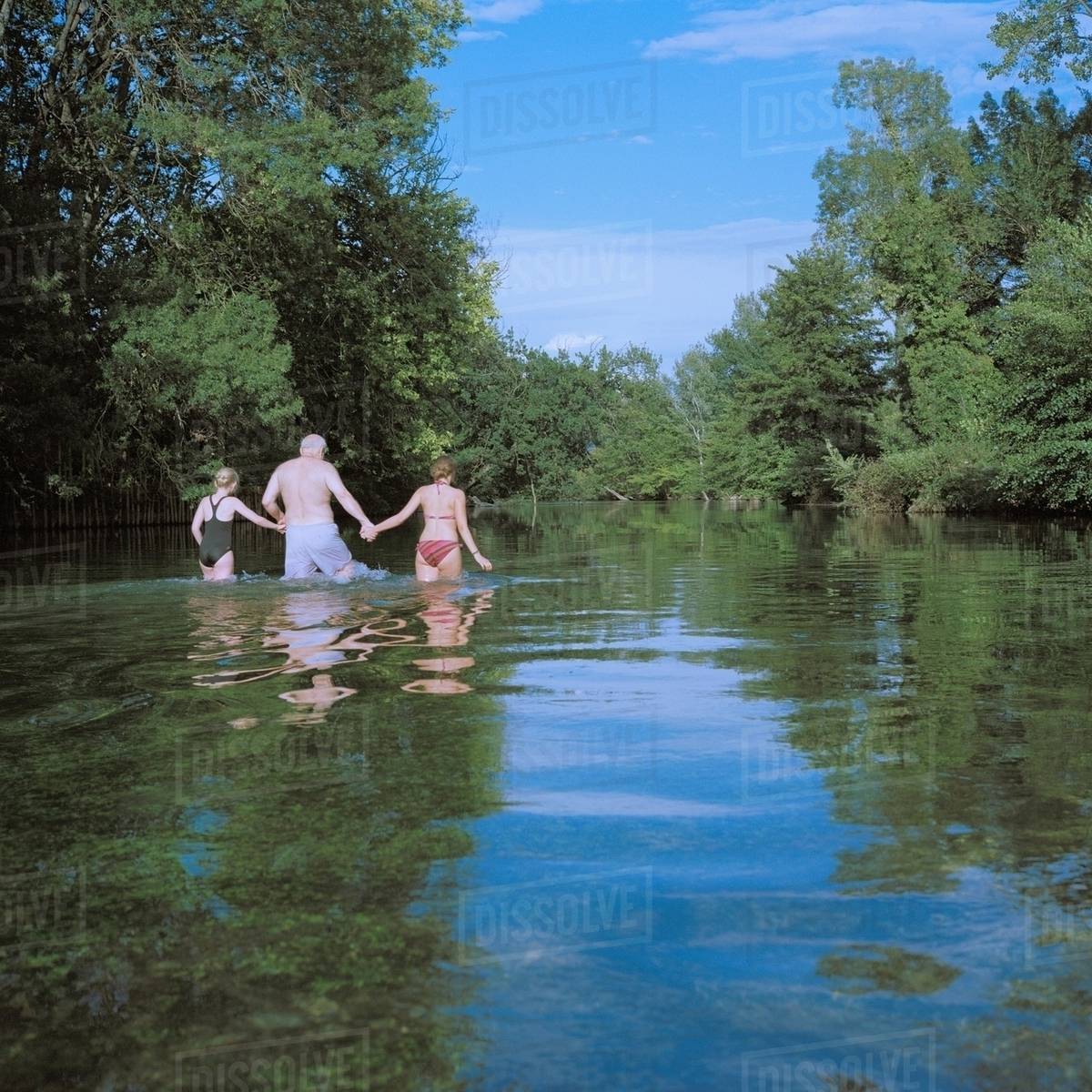 Man and two girls wading in river - Royalty-free Stock Photo | Dissolve