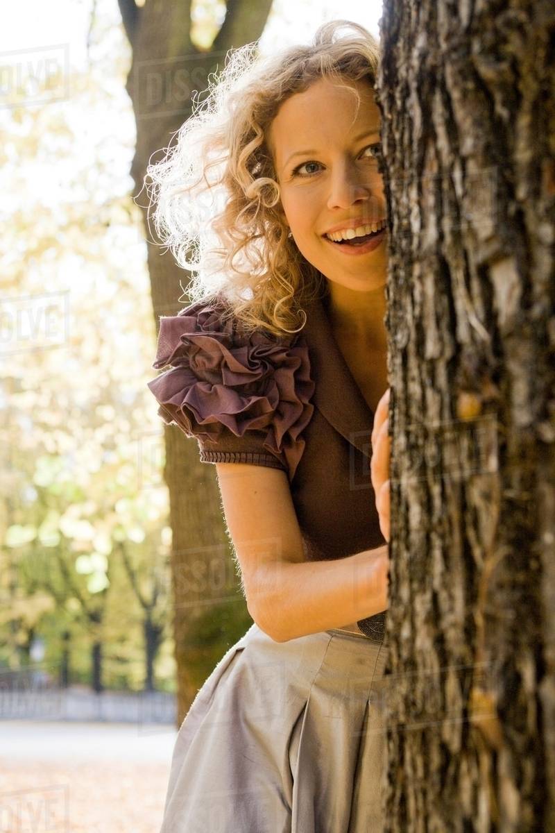Woman hiding behind tree - Royalty-free Stock Photo | Dissolve