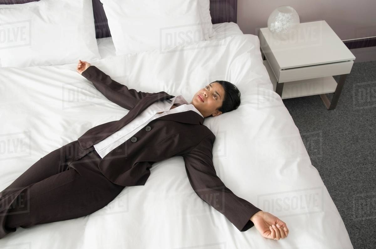 Woman on a bed with arms outstretched - Royalty-free Stock Photo | Dissolve