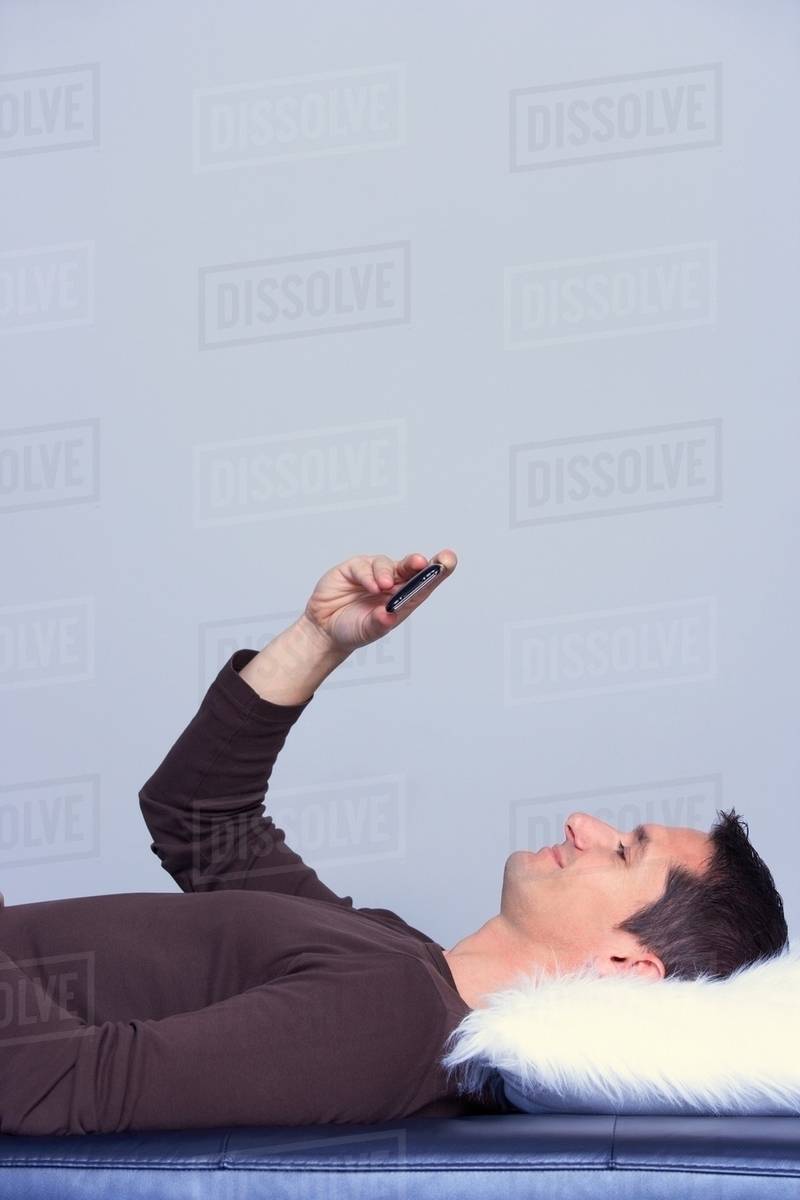 Man lying checking his phone - Royalty-free Stock Photo | Dissolve