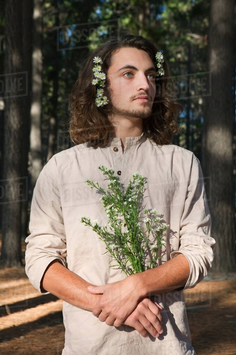 Man holding flowers in forest - Royalty-free Stock Photo | Dissolve