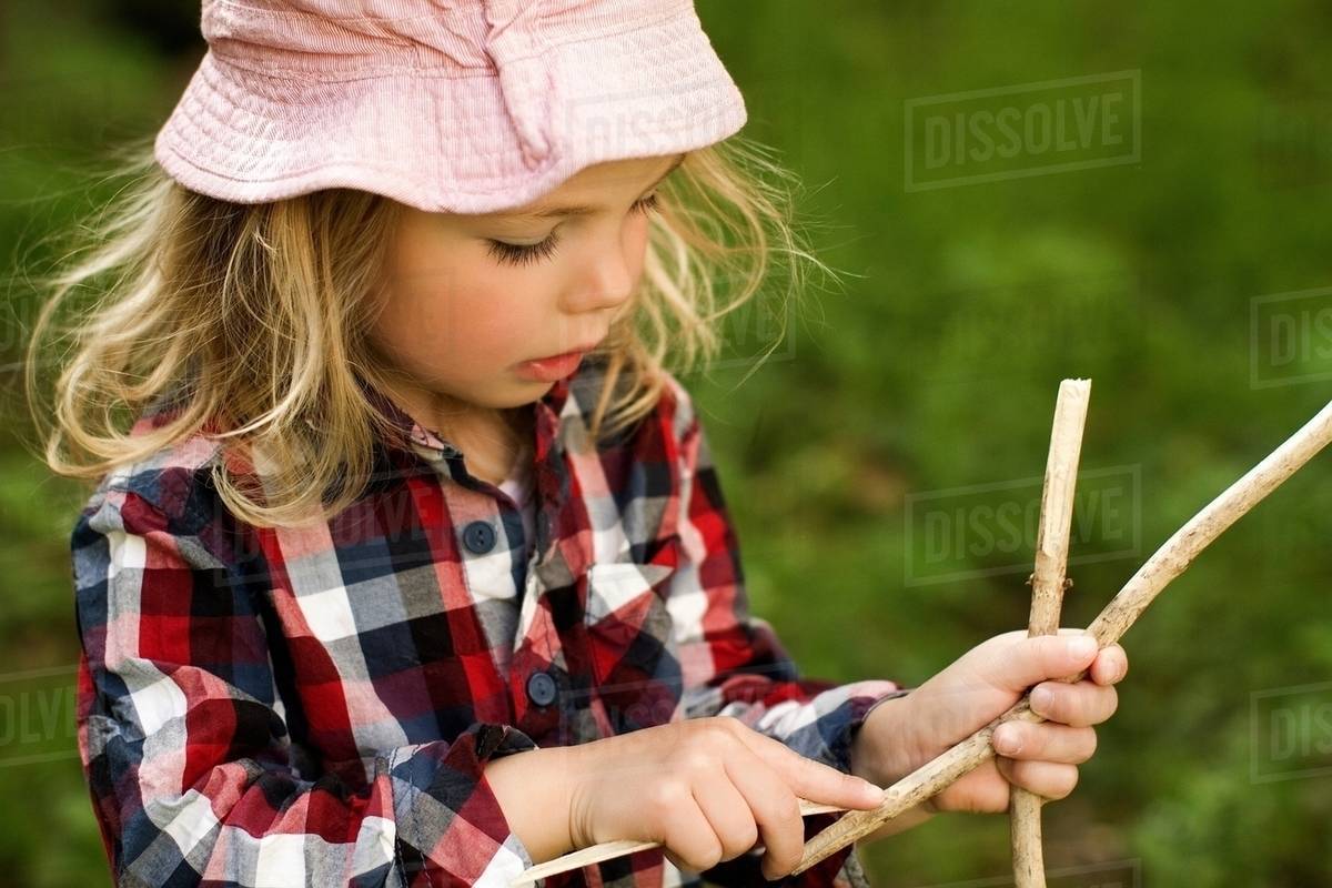 Girl playing with sticks outdoors - Stock Photo - Dissolve