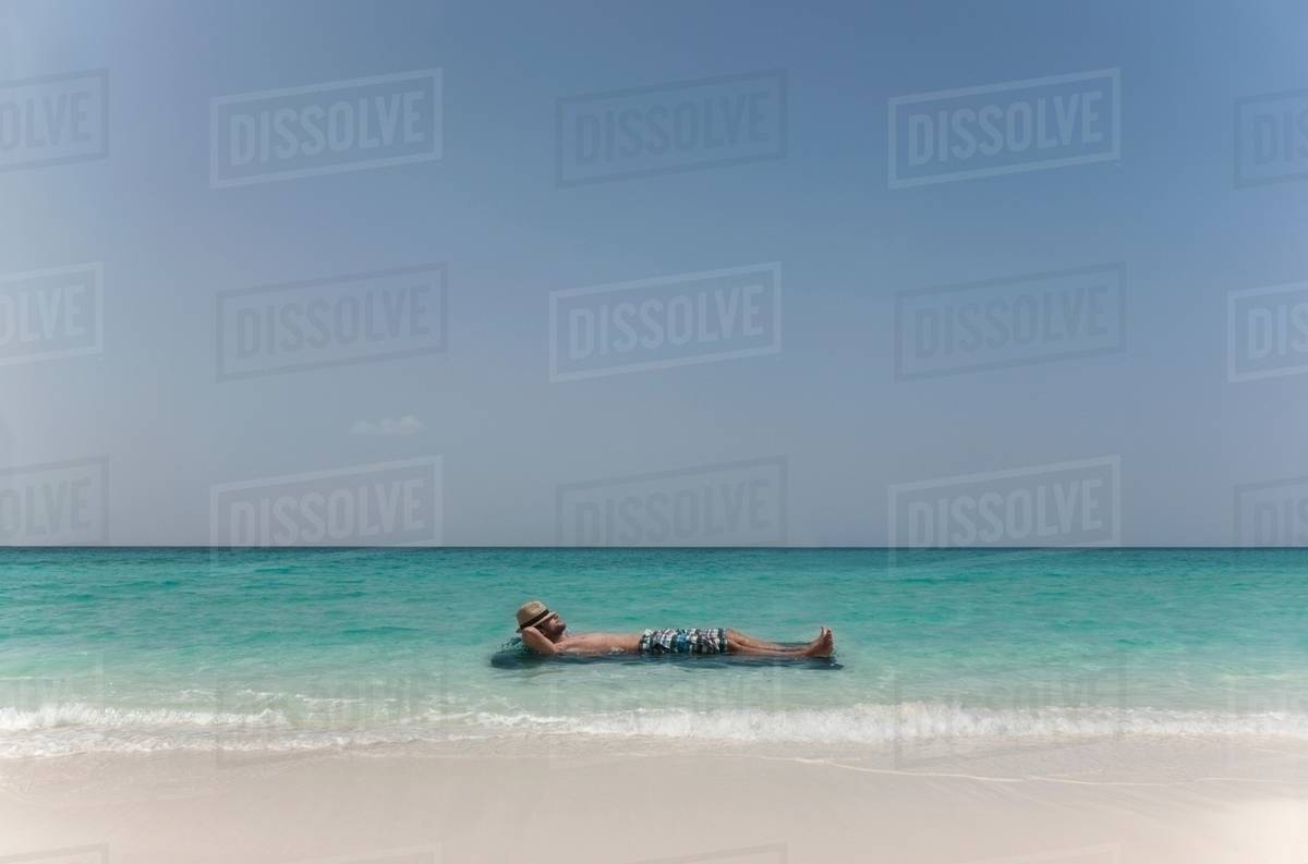 Man floating in water at tropical beach - Stock Photo - Dissolve