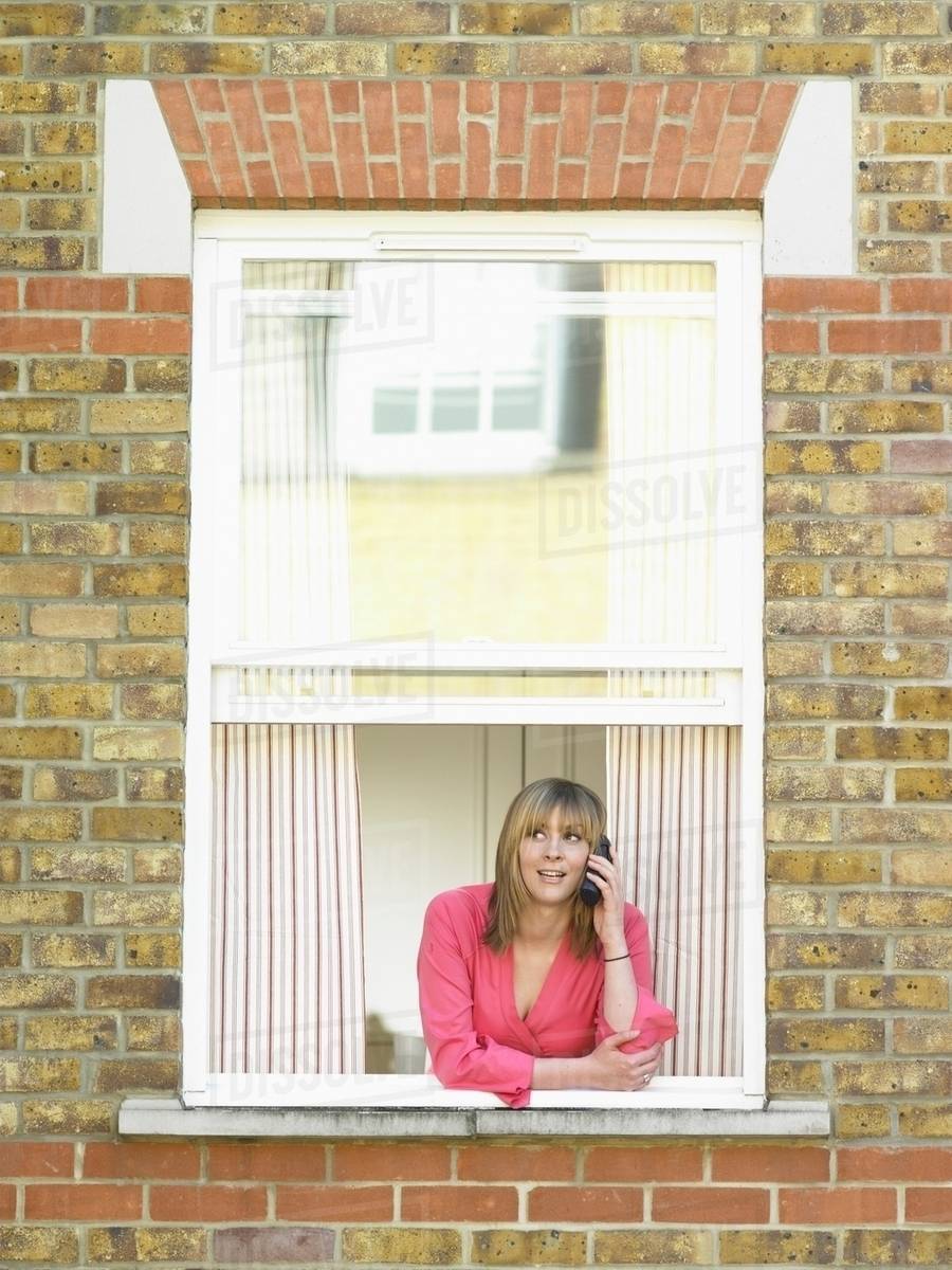 Woman talking on phone in window - Stock Photo - Dissolve