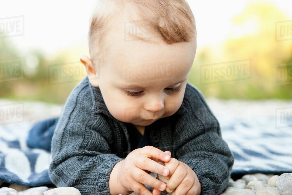 Baby playing with pebbles outdoors - Stock Photo - Dissolve