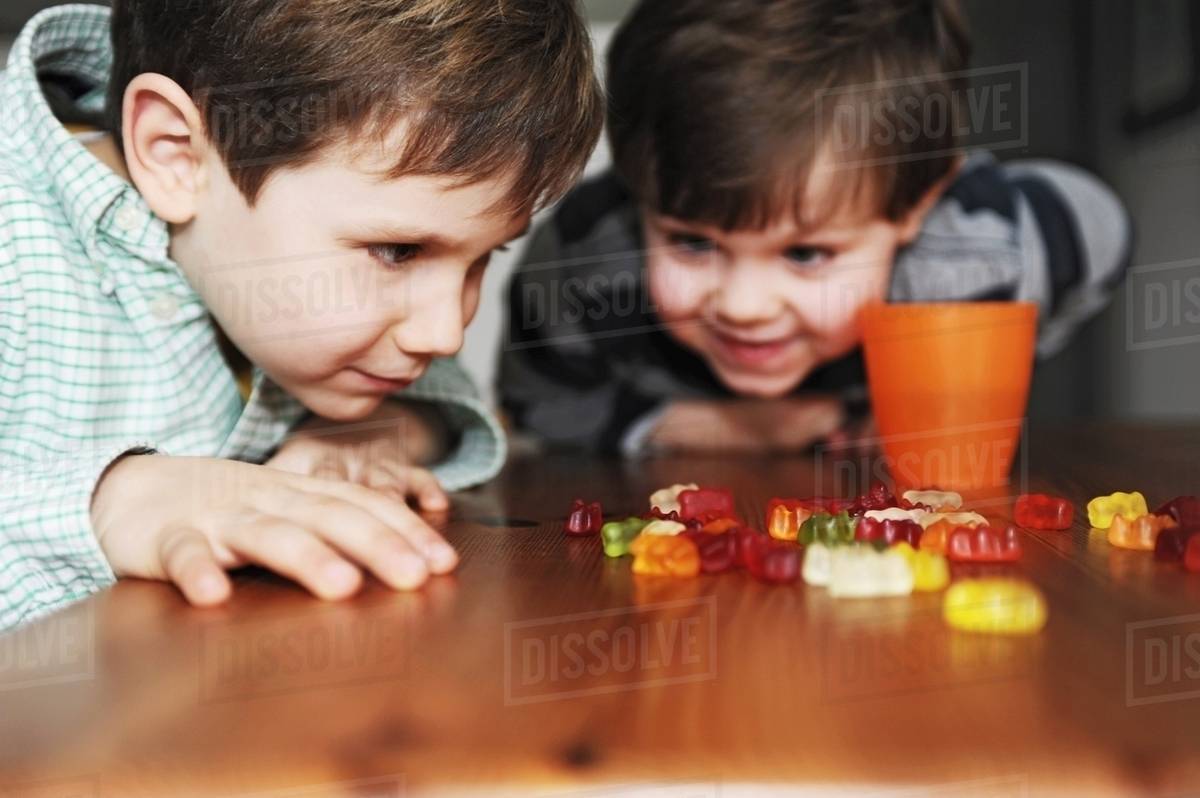 Boys playing with candy at table - Royalty-free Stock Photo | Dissolve