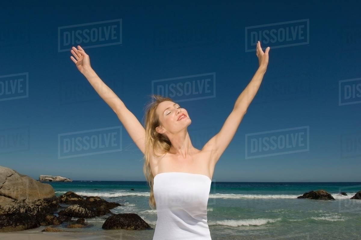 Woman with arms outstretched on beach - Royalty-free Stock Photo | Dissolve