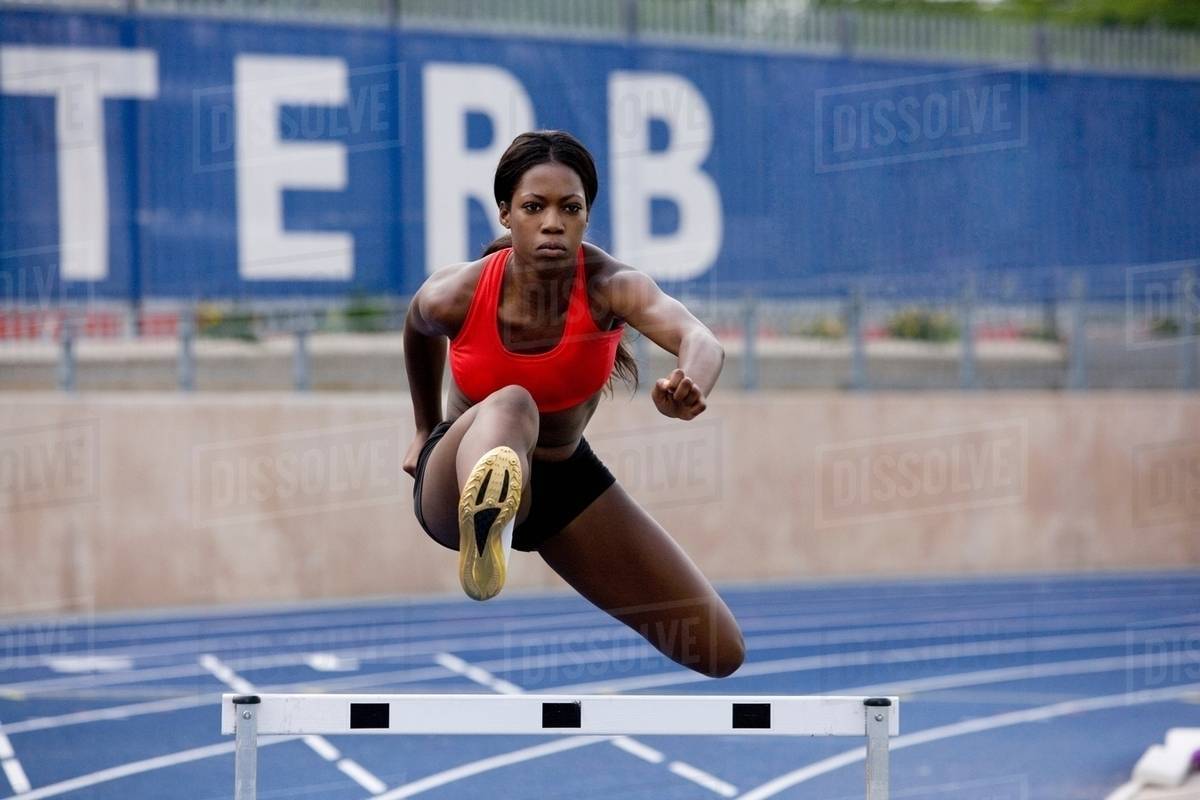Runner jumping over hurdles on track - Royalty-free Stock Photo | Dissolve