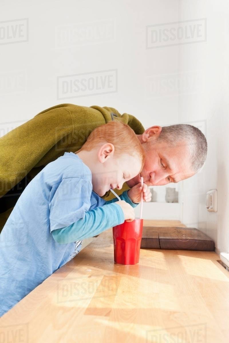 Father and son drinking with straws - Stock Photo - Dissolve