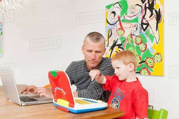 Father and son working on laptops - Stock Photo - Dissolve