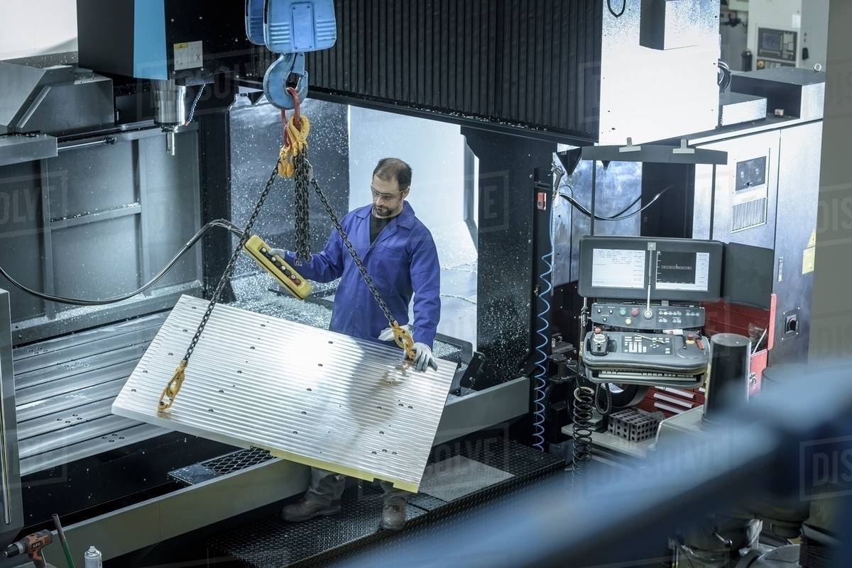 Overview of worker with large CNC machine in plastics factory - Stock ...